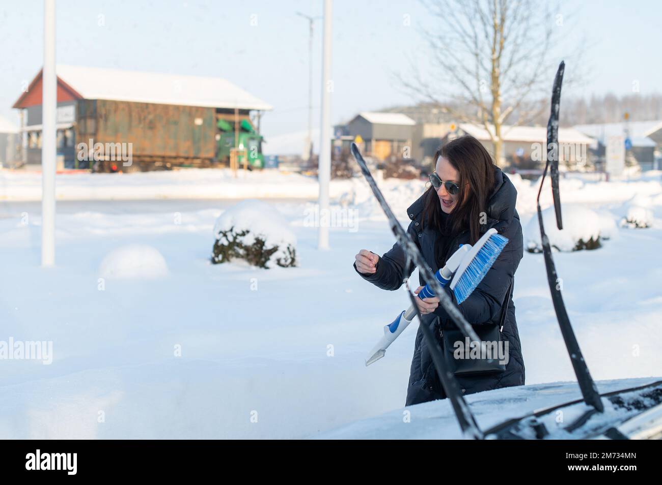 Woman cleans car with a brush from snow after a blizzard Stock Photo ...