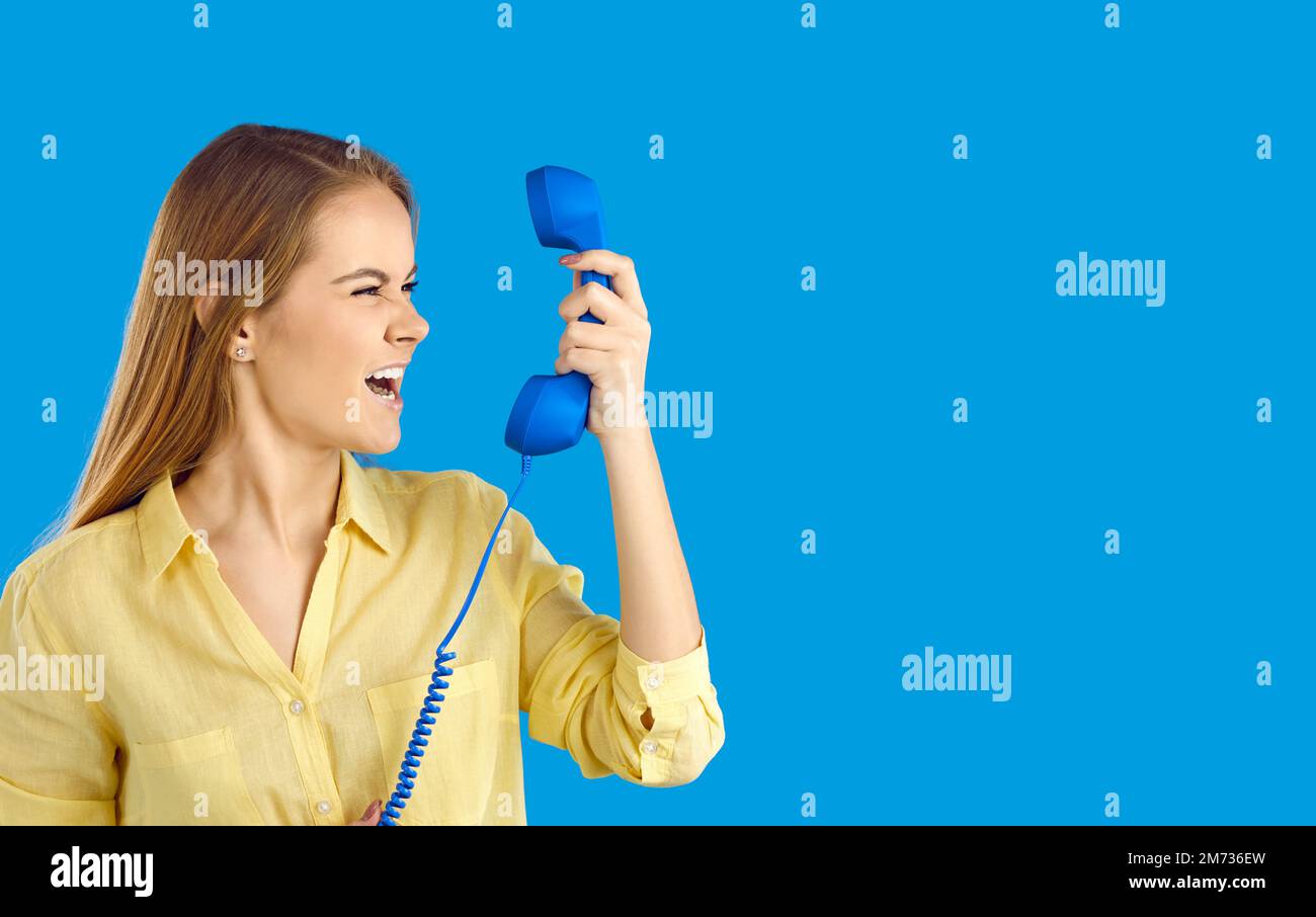 Angry irritated young woman standing talking on telephone screaming ...