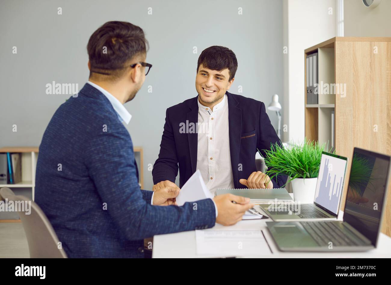 Two colleagues in office are talking discussing new project or task and ...