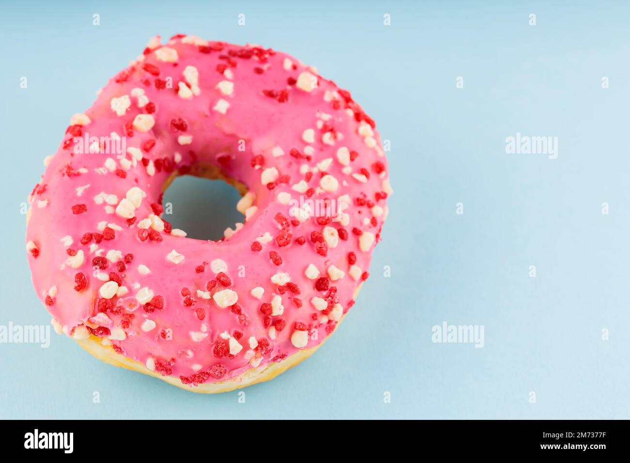 Pink sweet donut with pink sprinkles. Delicious glazed donut on blue ...