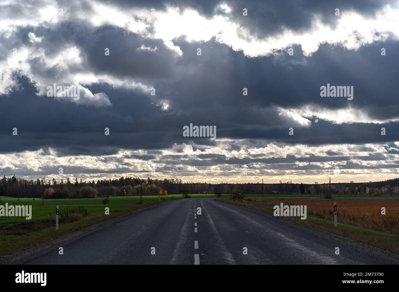 Dramatic sky with dark rain clouds over asphalt country road in autumn ...