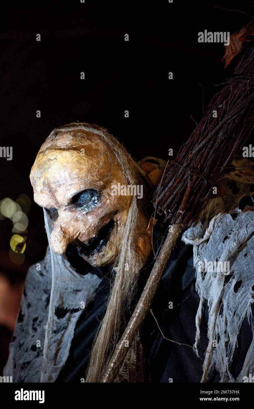 Witch with a broom and a monster face on a dark halloween horror night ...