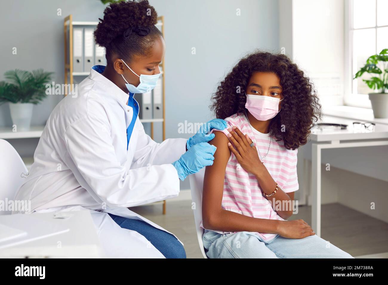 African American teenage girl receives flu shot during seasonal ...