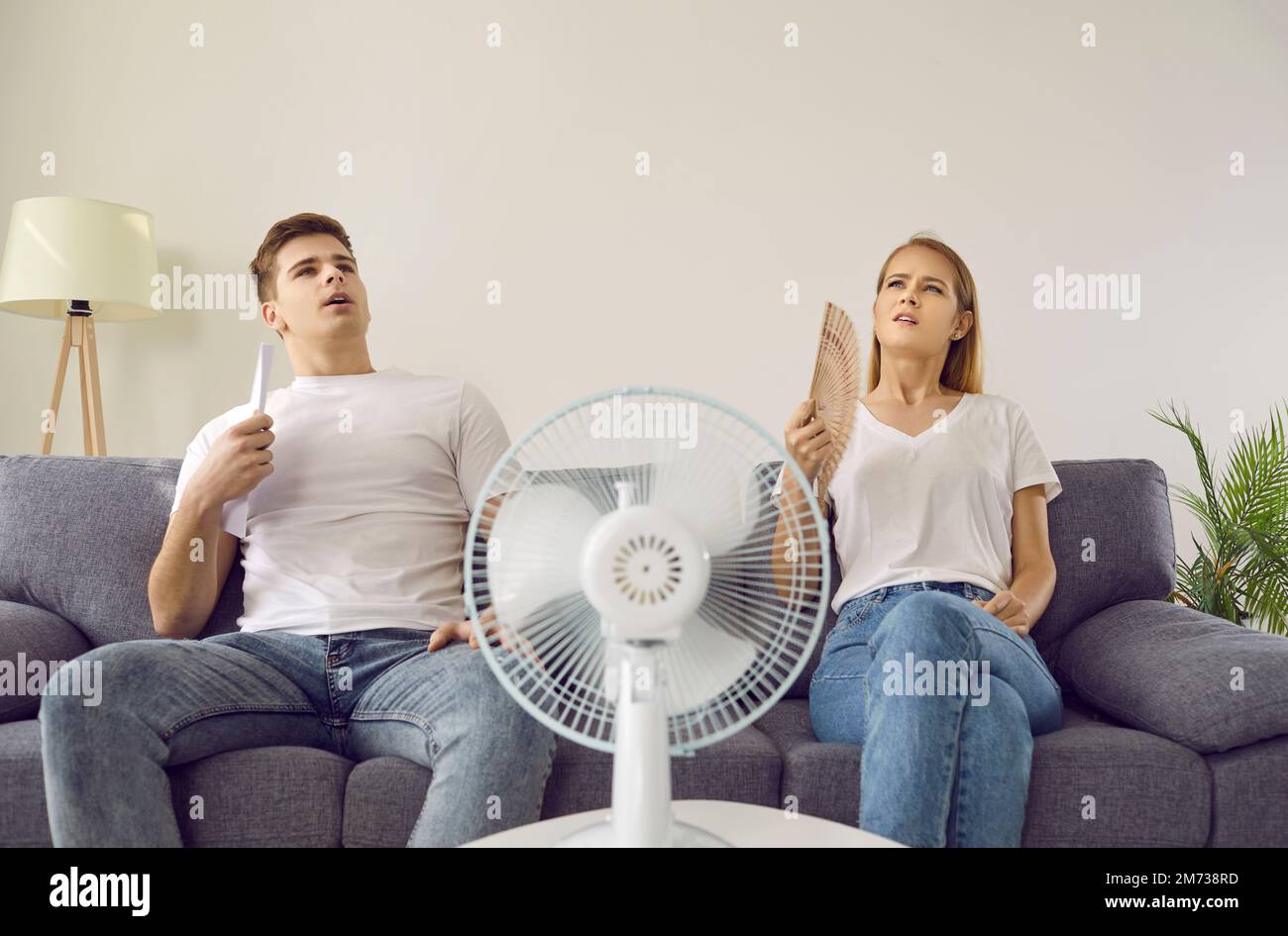 Young couple who are tired from extremely hot summer weather use ...