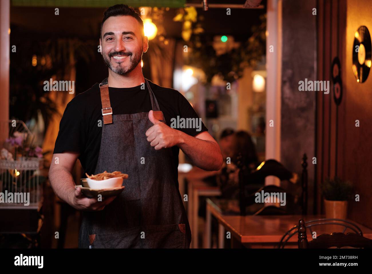 Waiter showing thumb up and smiling while holding a plate with food in ...