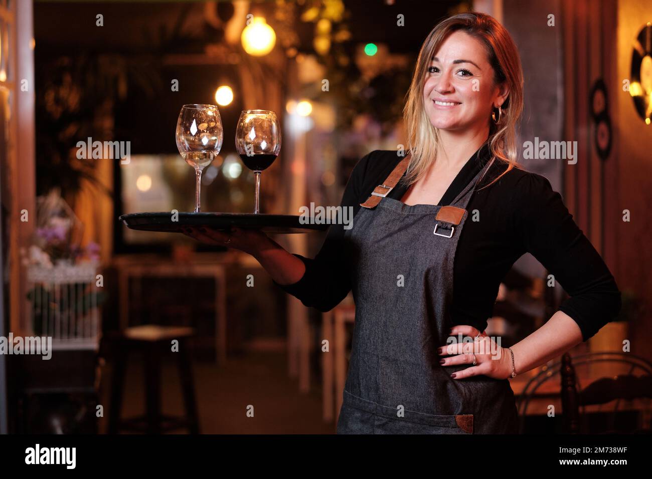 Waitress looking at the camera and smiling while posing holding a tray ...