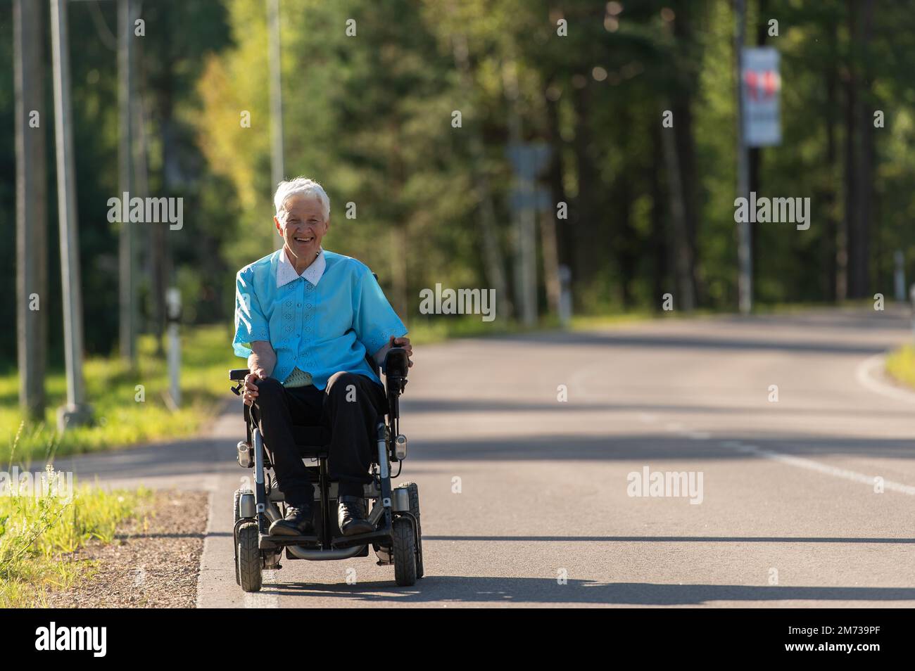 Smiling disabled old woman in a wheelchair on the highway Stock Photo ...