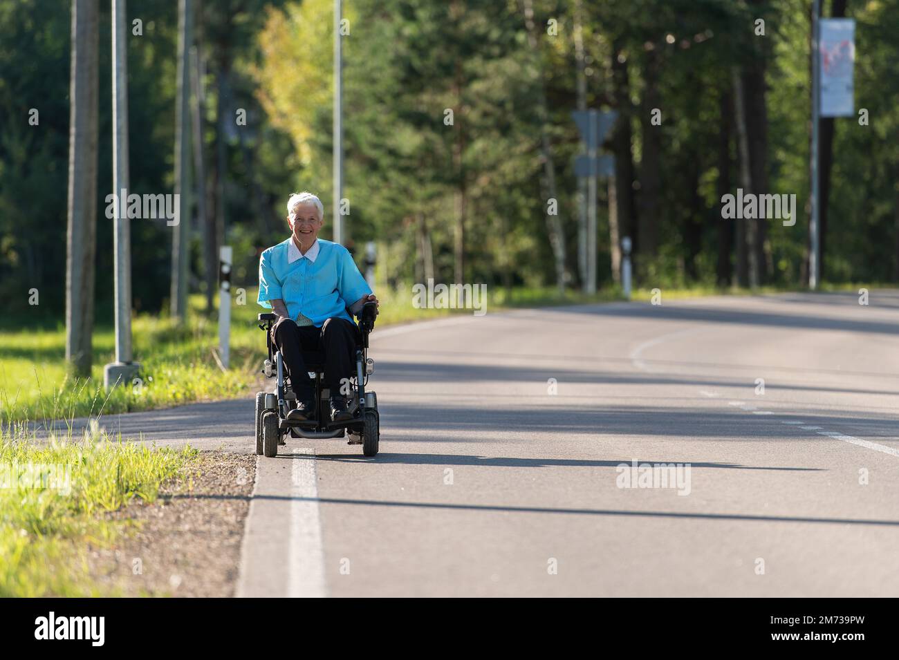 Smiling disabled old woman in a wheelchair on the highway Stock Photo ...