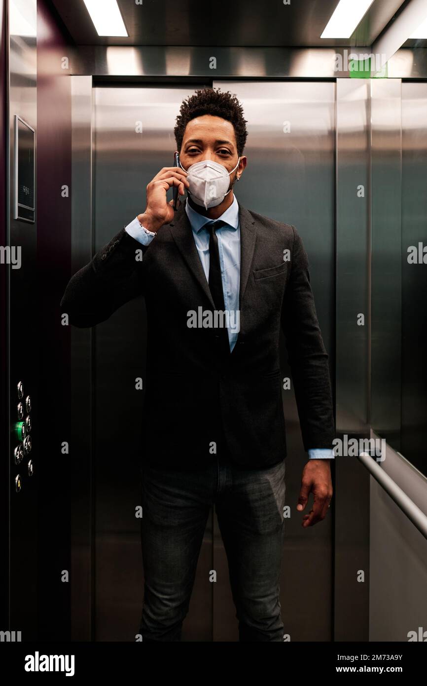 Businessman with face mask talking on the phone while standing in the ...