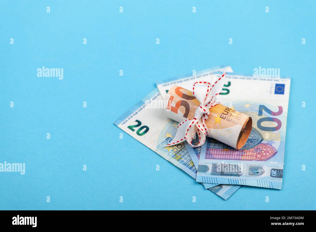 rolled into a roll of 50 euros on a light blue background of 20 euro ...
