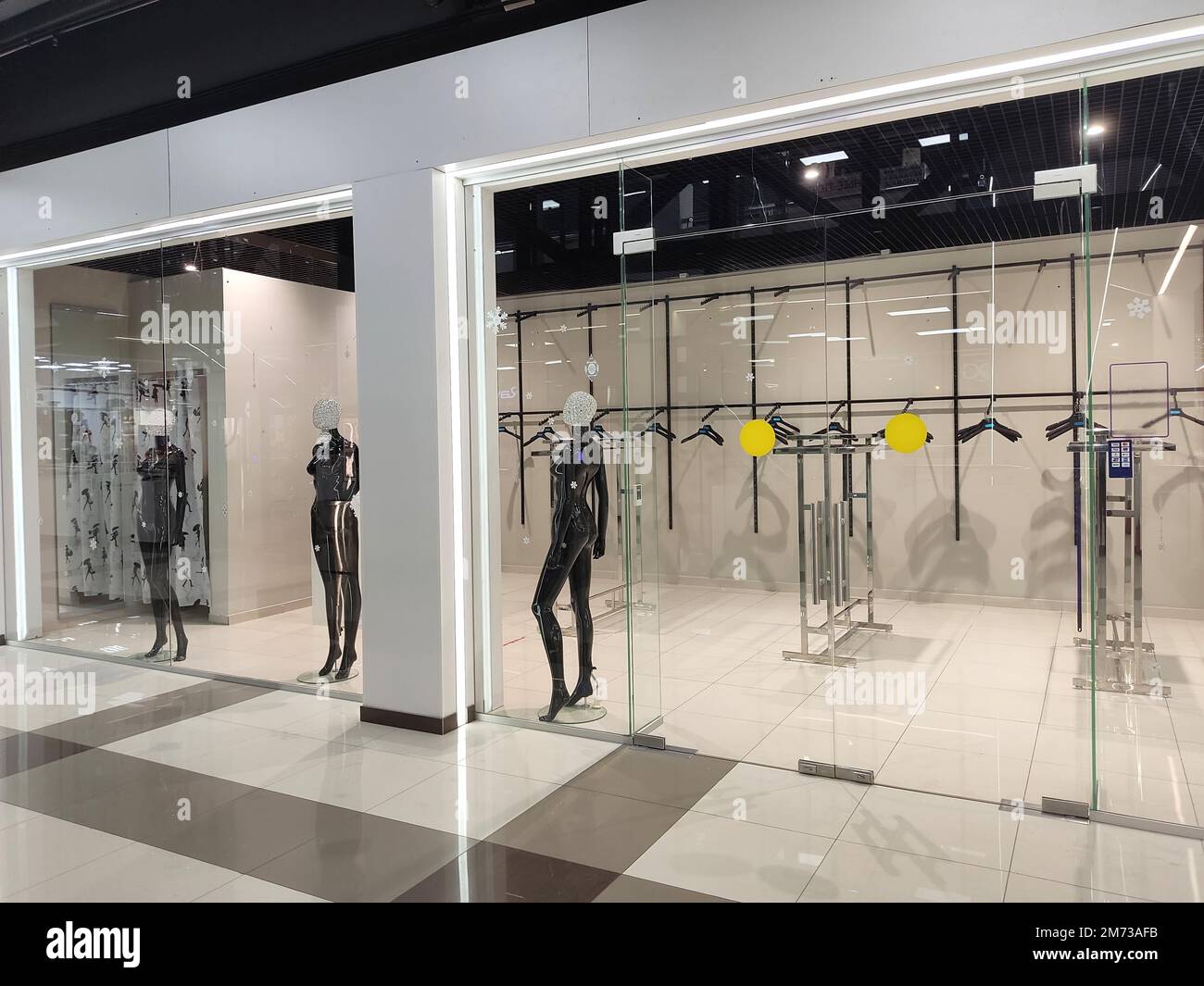 The window of an empty clothing store with black mannequins and empty ...