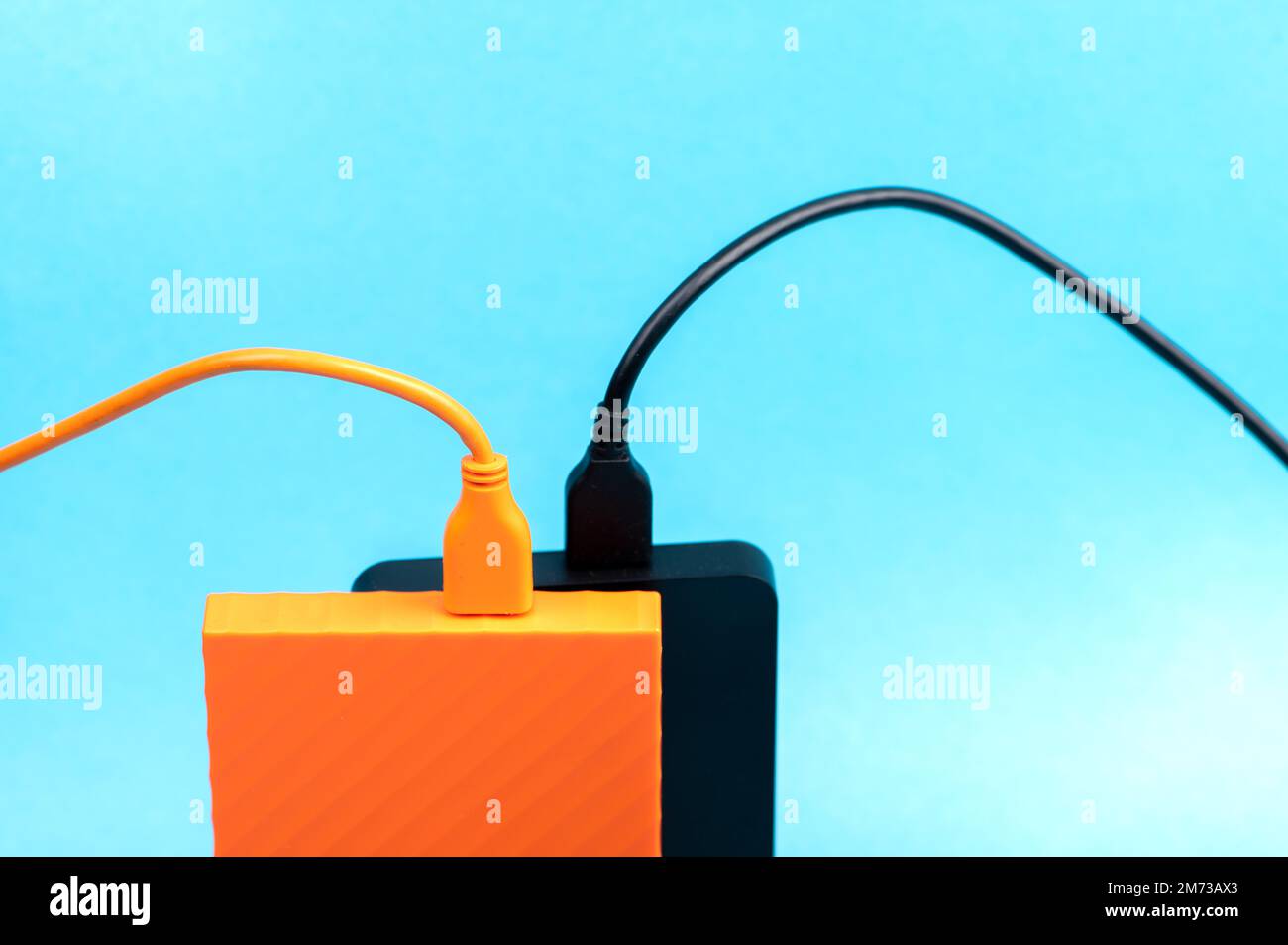 Two external portable hard disk drives isolated on light blue ...