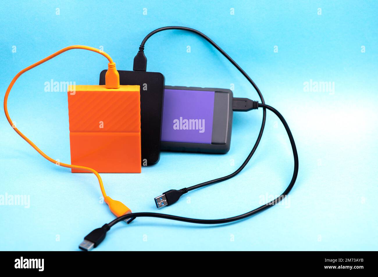 Three external portable hard disk drives isolated on light blue ...