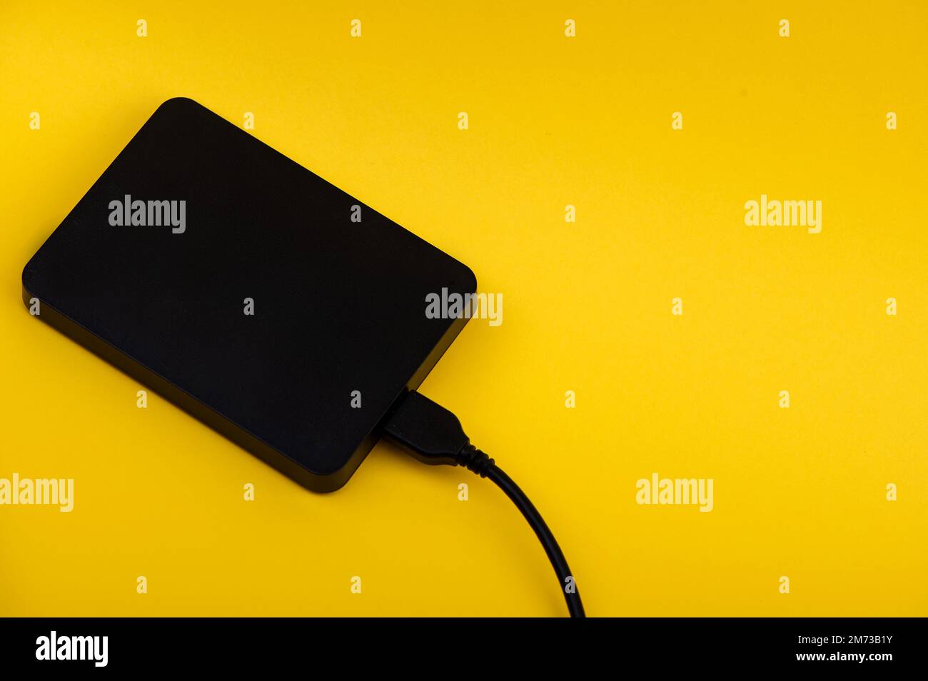 Black external portable hard disk drives isolated on yellow background ...