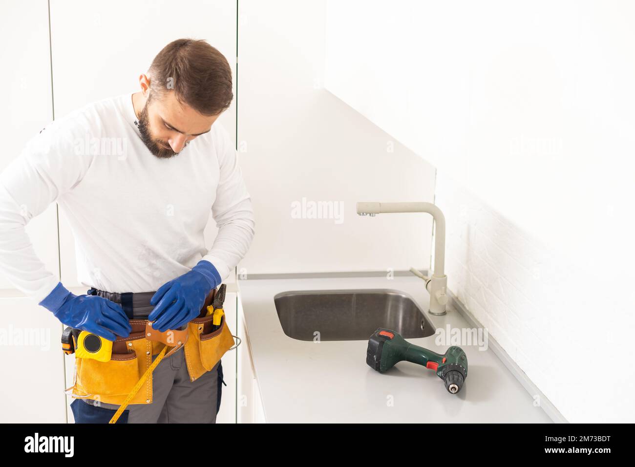 Side View Of A Plumber Fixing Water Tap In Kitchen Stock Photo - Alamy