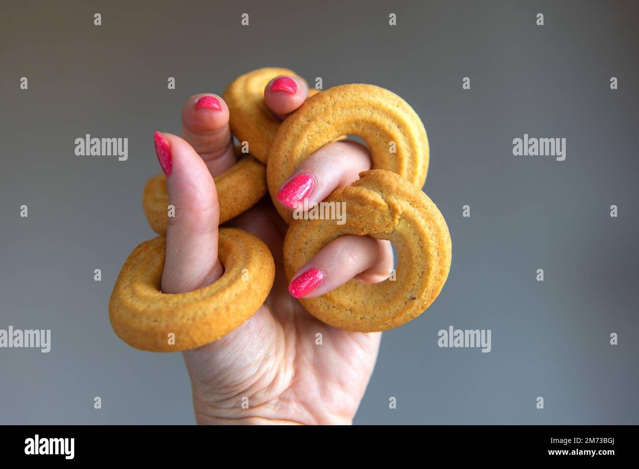 butter cookies rings on the fingers of a woman's hand on a gray ...