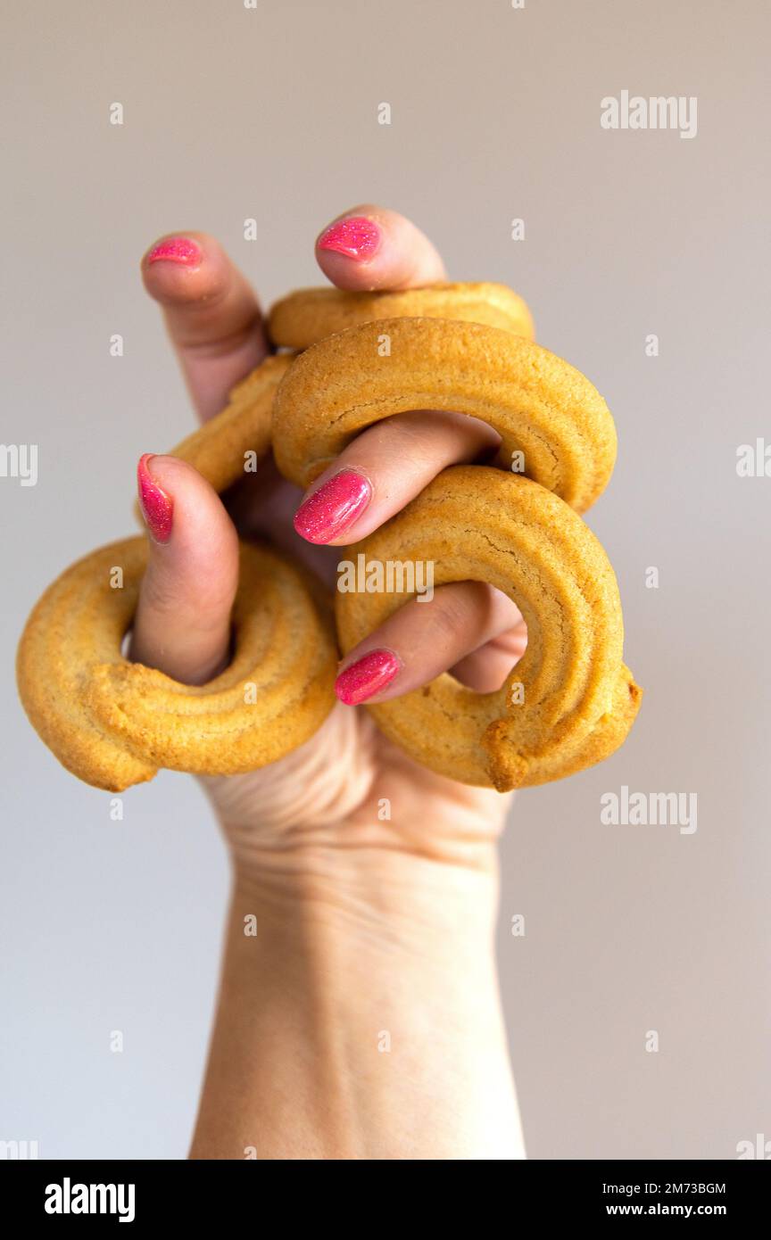 butter cookies rings on the finger of a woman's hand on a gray ...