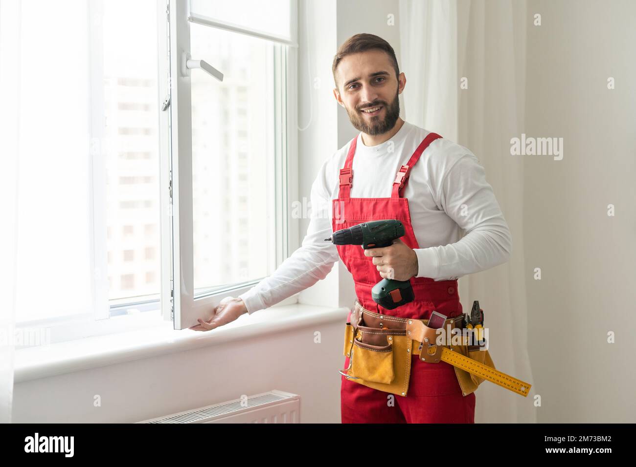 service man installing window with screwdriver Stock Photo - Alamy