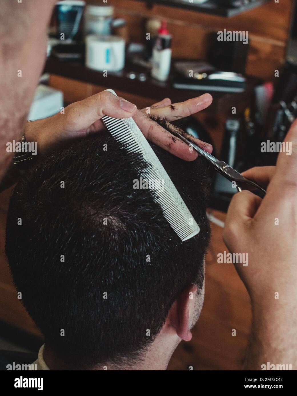A vertical closeup shot of a male barber working with a comb and ...