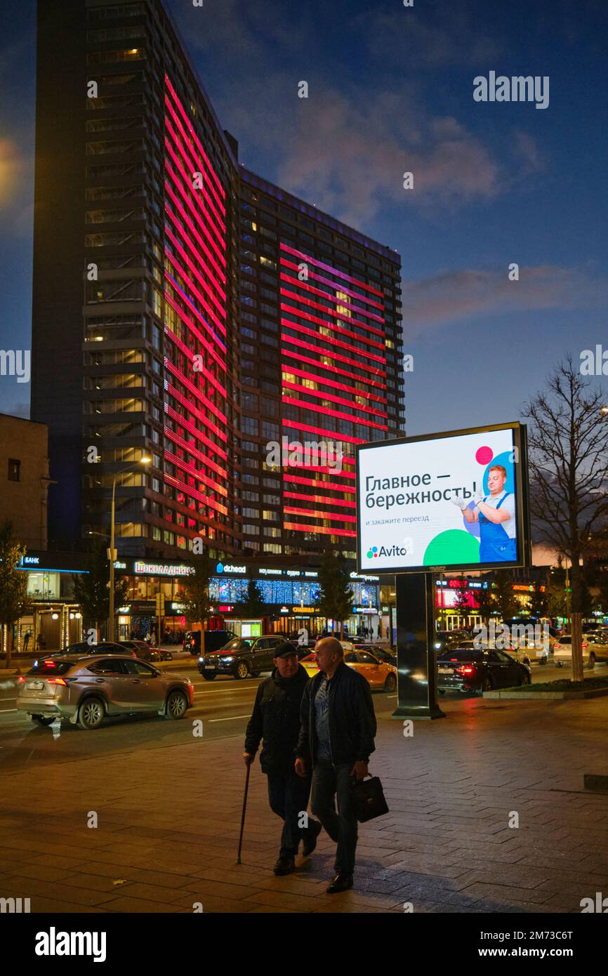 Two older men walk along the sidewalk at dusk together. Novy Arbat (New ...