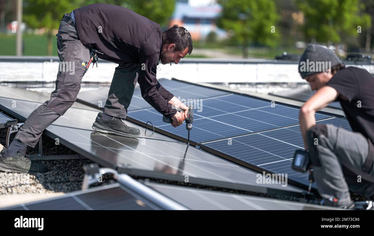 Male team engineers installing stand-alone solar photovoltaic panel ...