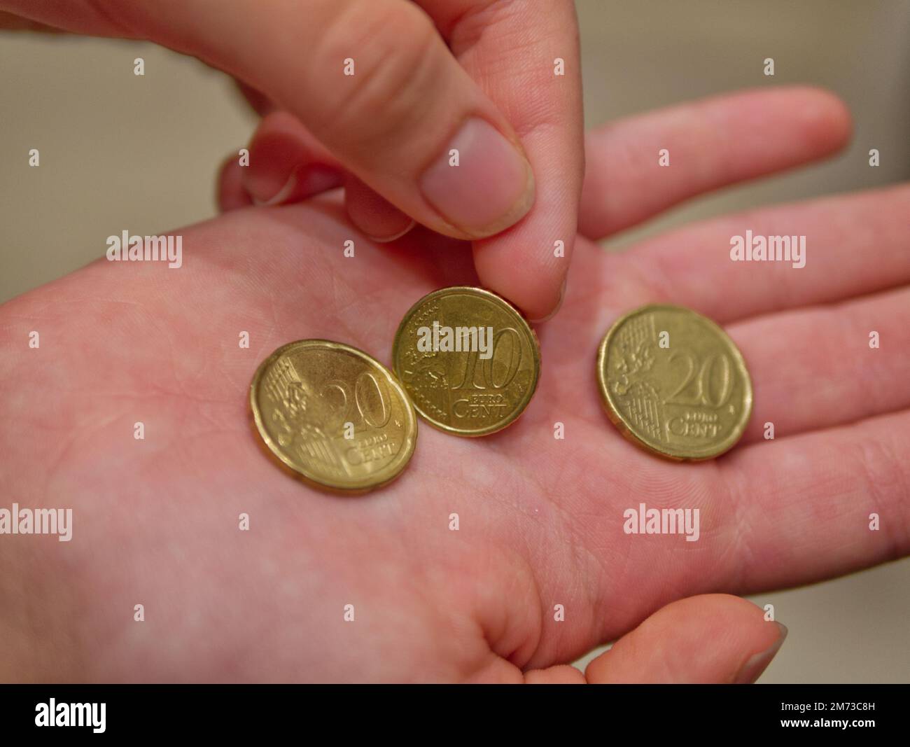 Girl holds euro coins of 10 and 20 cents in hand Stock Photo - Alamy