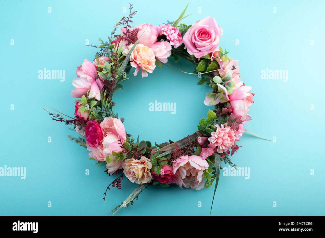 Colorful artificial flowers wreath isolated on light aqua green ...