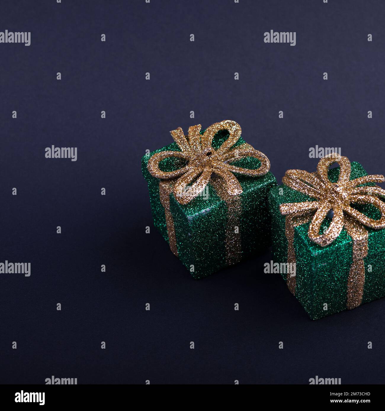 Christmas decor green gift box with shiny gold bow on dark square ...