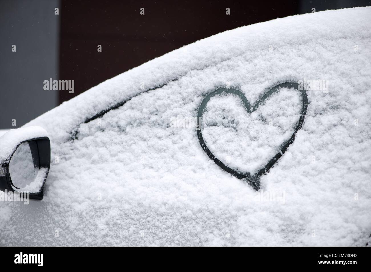 Lovely heart symbol drawn by hand on snowy car window at day light ...