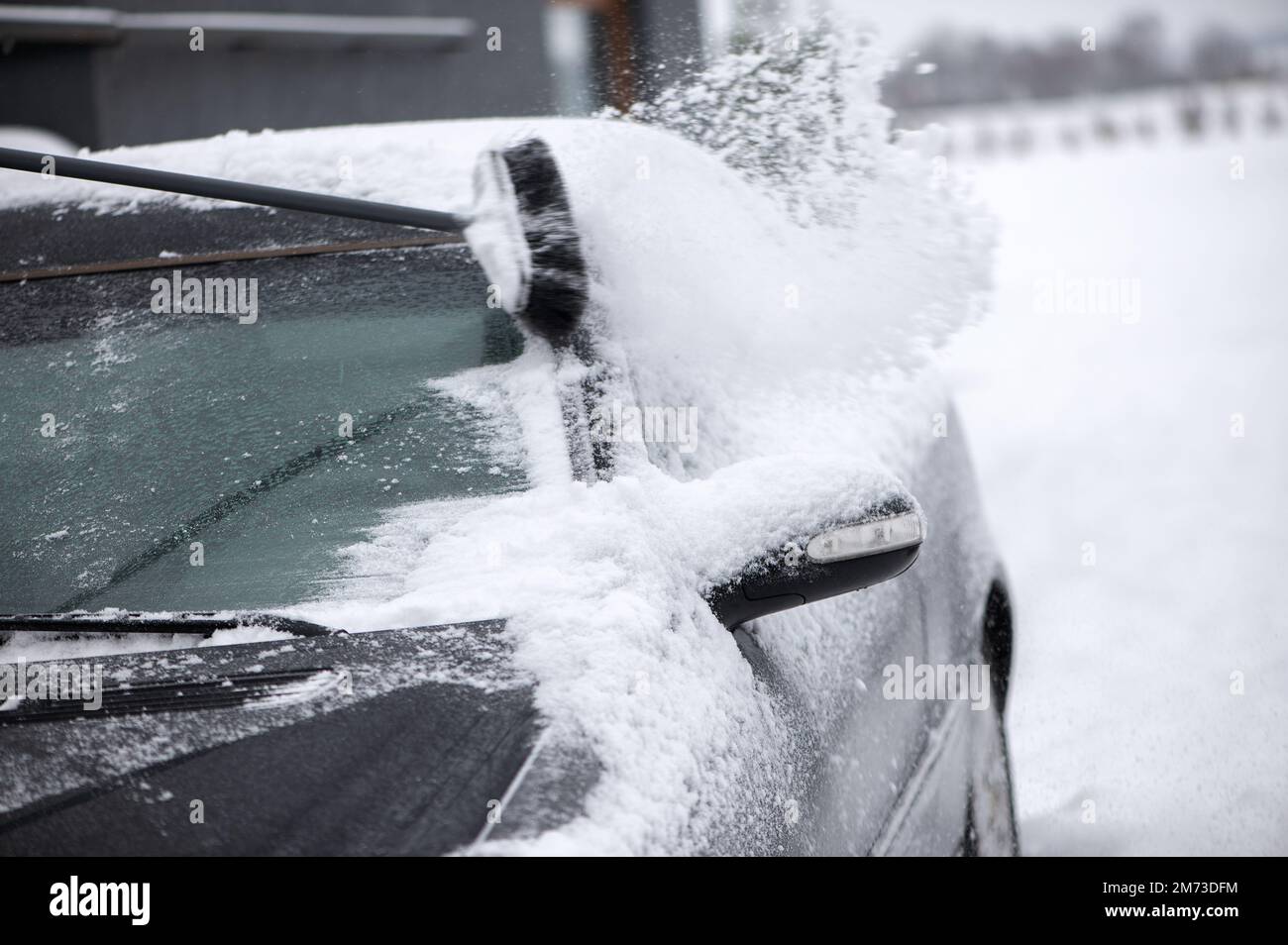 Man cleans the car from the snow with a brush. Bad snow weather concept ...
