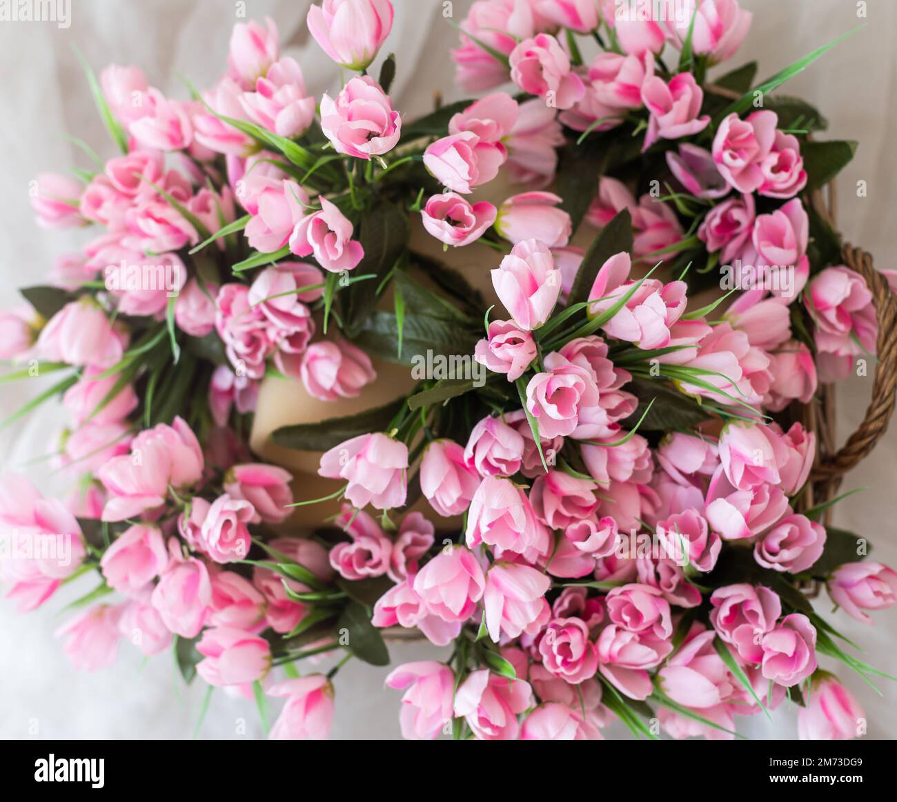 flowers in wicker basket on white wooden table, space for text. Spring ...