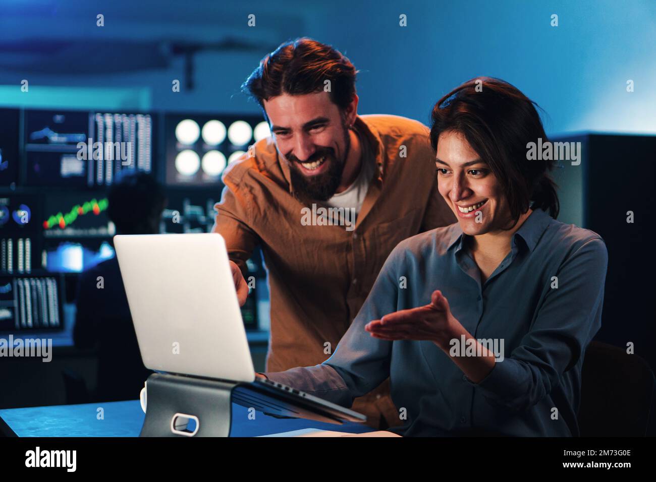 Happy business couple working on a laptop computer in the office. Young ...