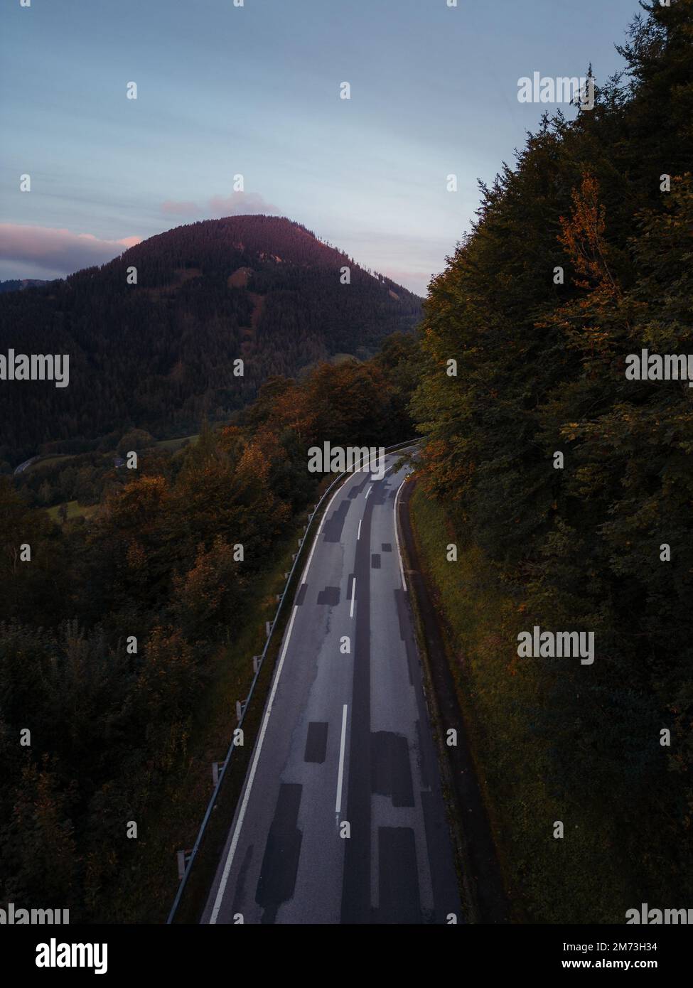 A vertical shot of a small road in the Austrian Alps during sunset ...