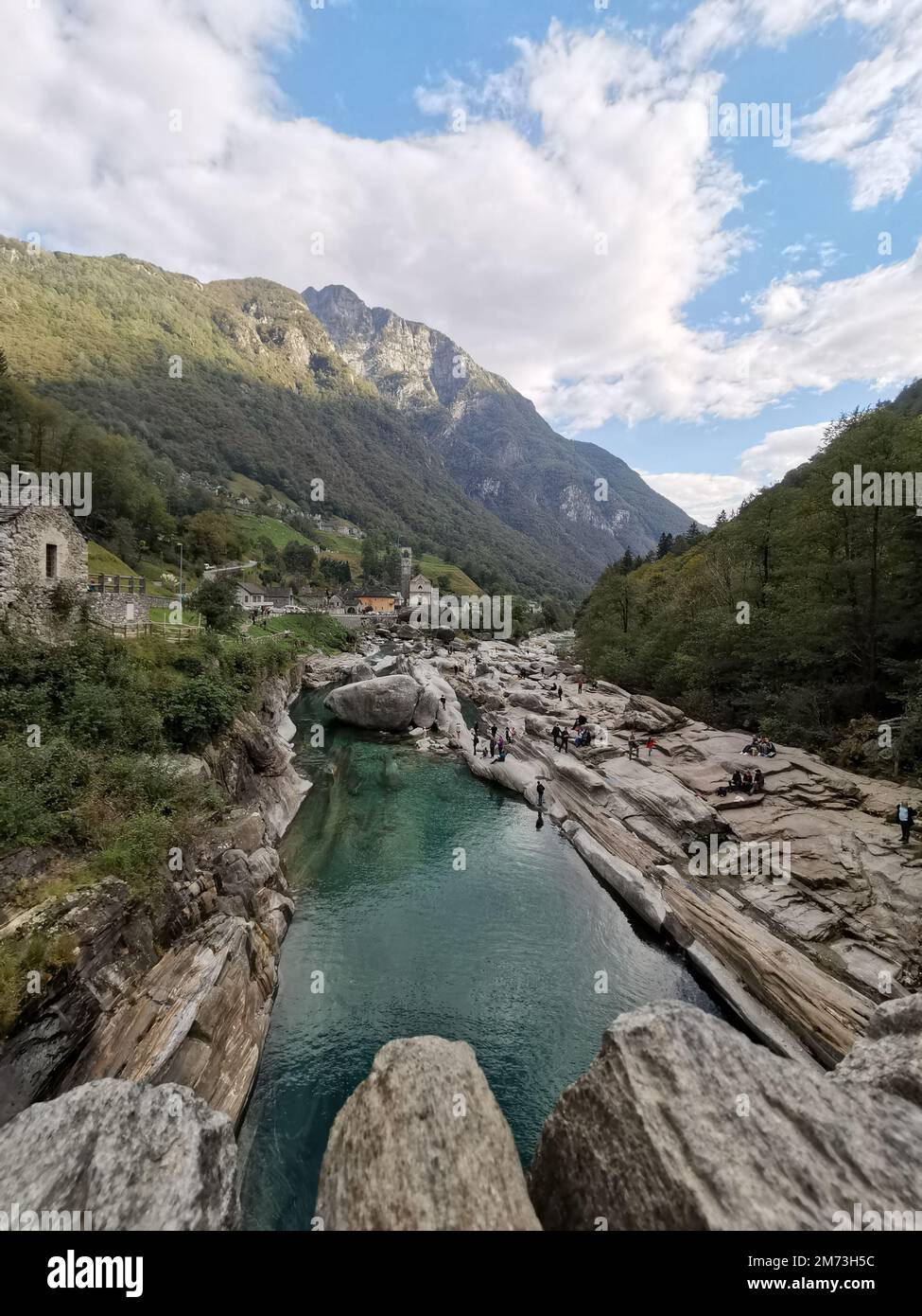 A vertical shot of a river with an imposing mountainscape at Valle ...