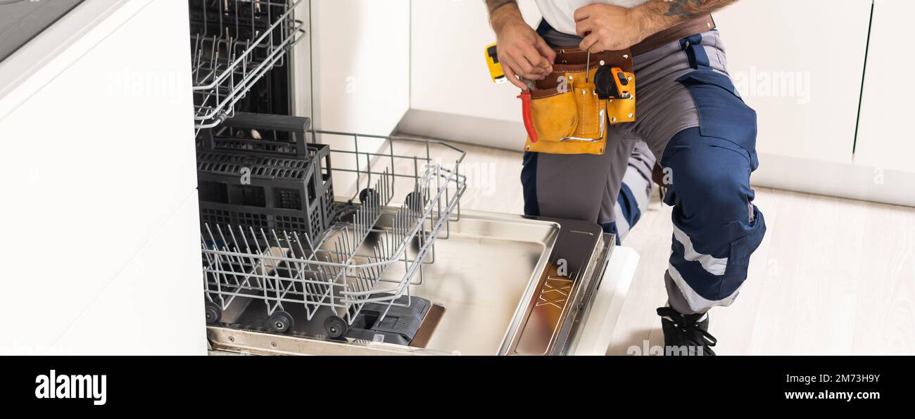Closeup repair and installation of dishwasher, male worker with tool in ...