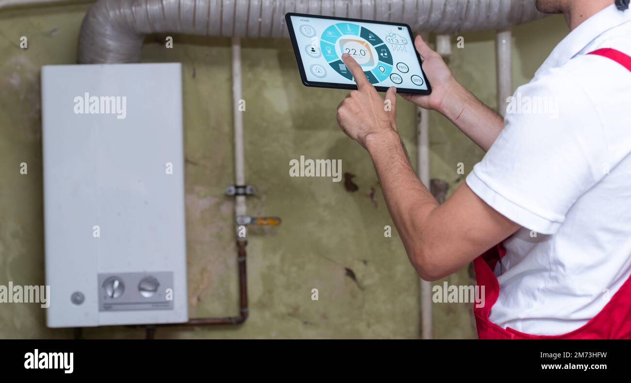 Man is Adjusting a temperature on the thermostat using a tablet with ...