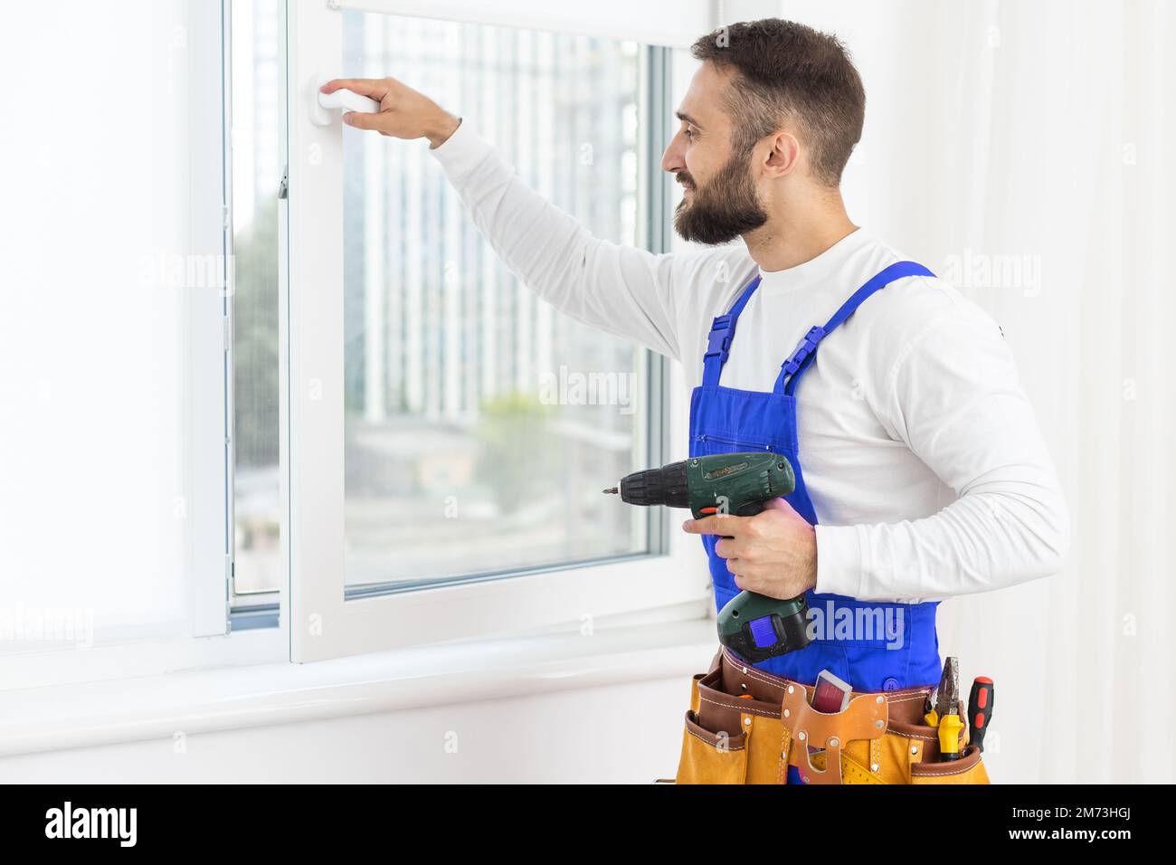 service man installing window with screwdriver Stock Photo - Alamy