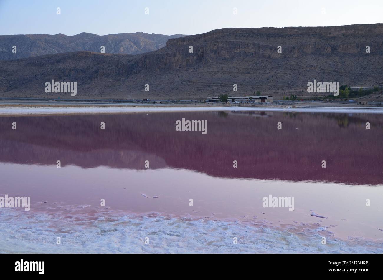 mountain range reflects in the evening light in the pink coloured water ...