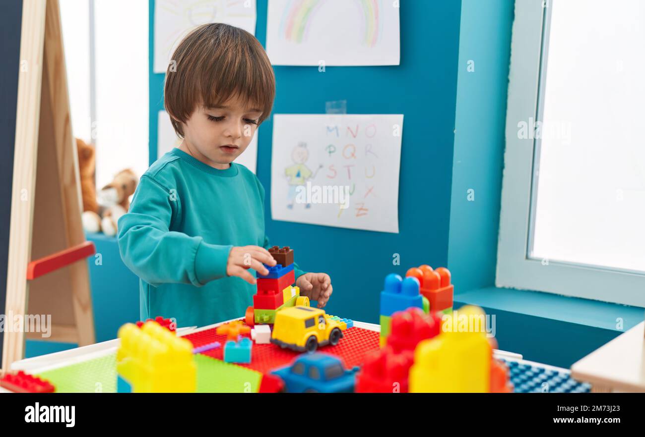 Adorable toddler playing with construction blocks standing at ...