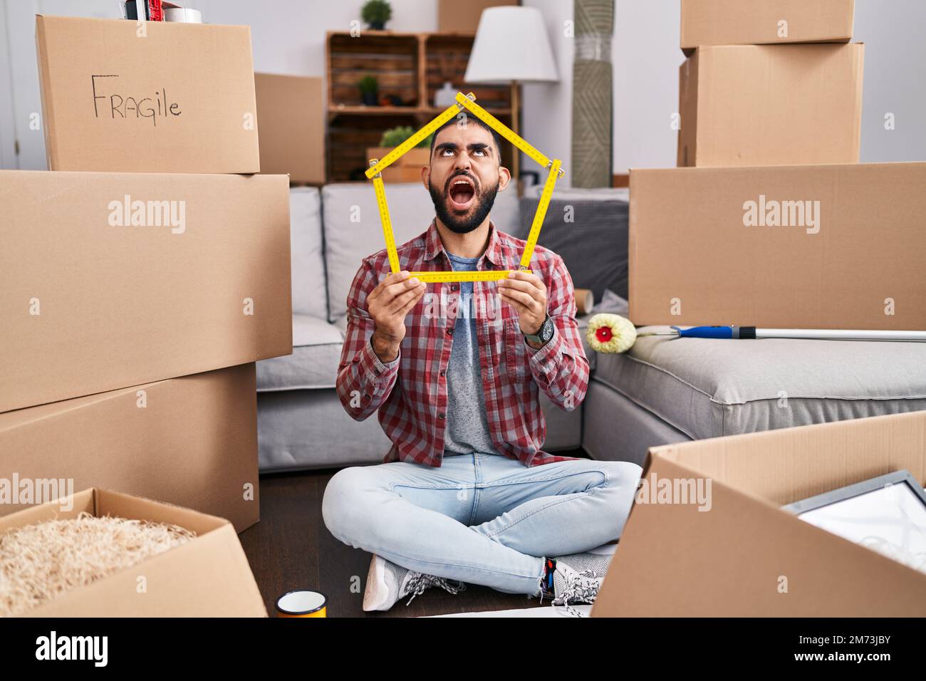 Middle east man with beard sitting on the floor at new home holding ...