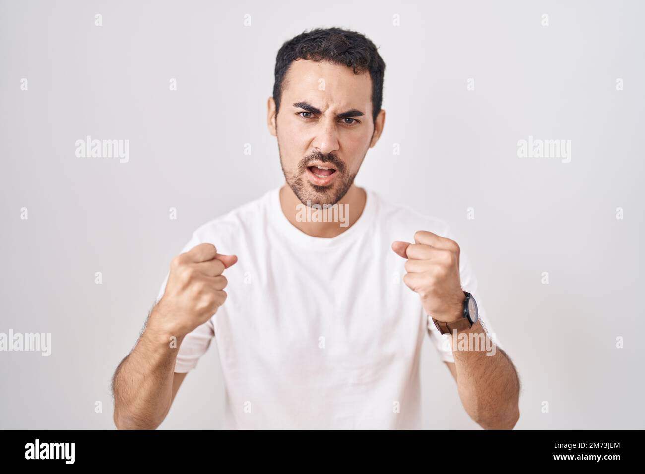 Handsome hispanic man standing over white background angry and mad ...