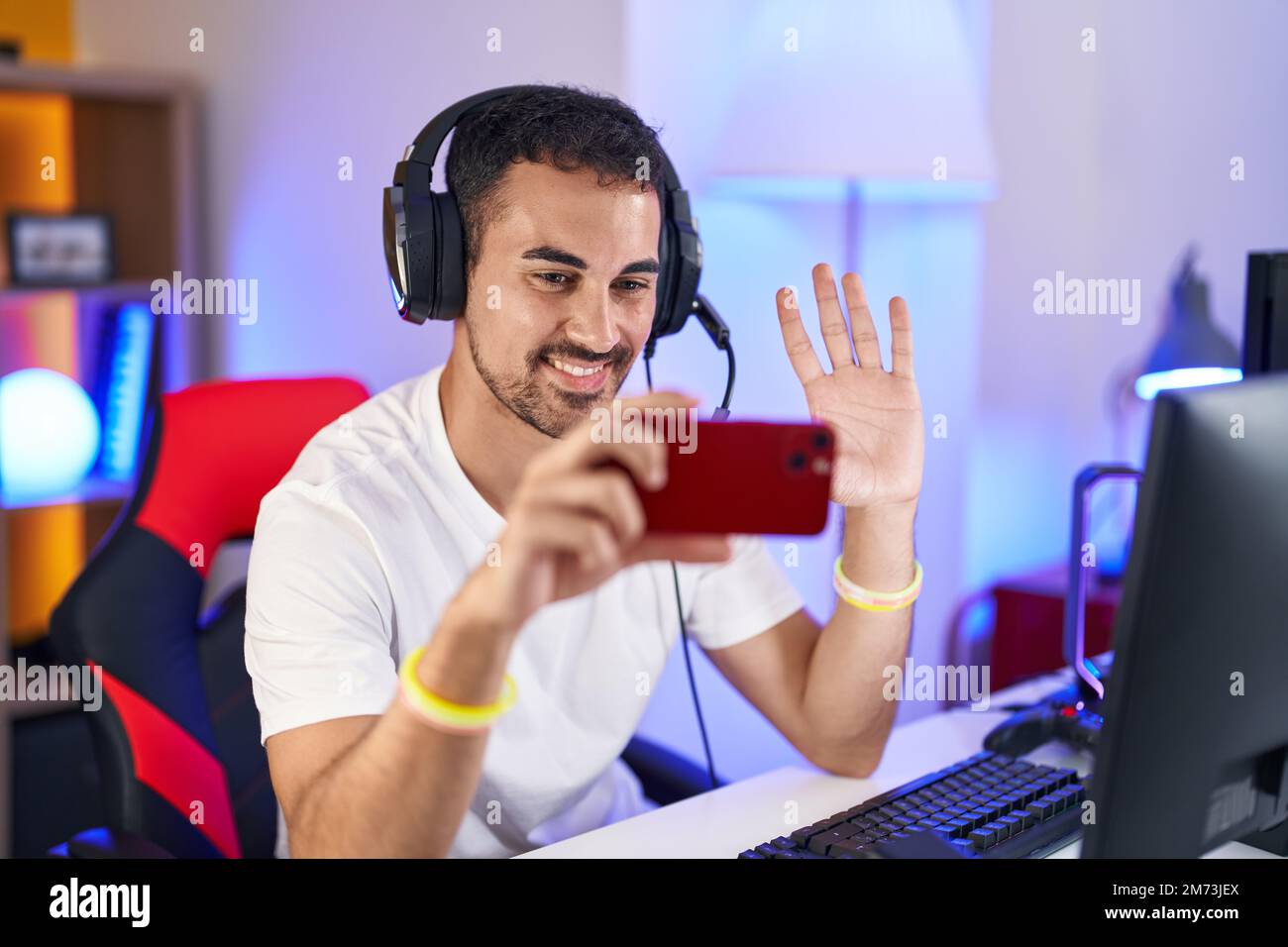 Handsome hispanic man playing video games with smartphone looking ...