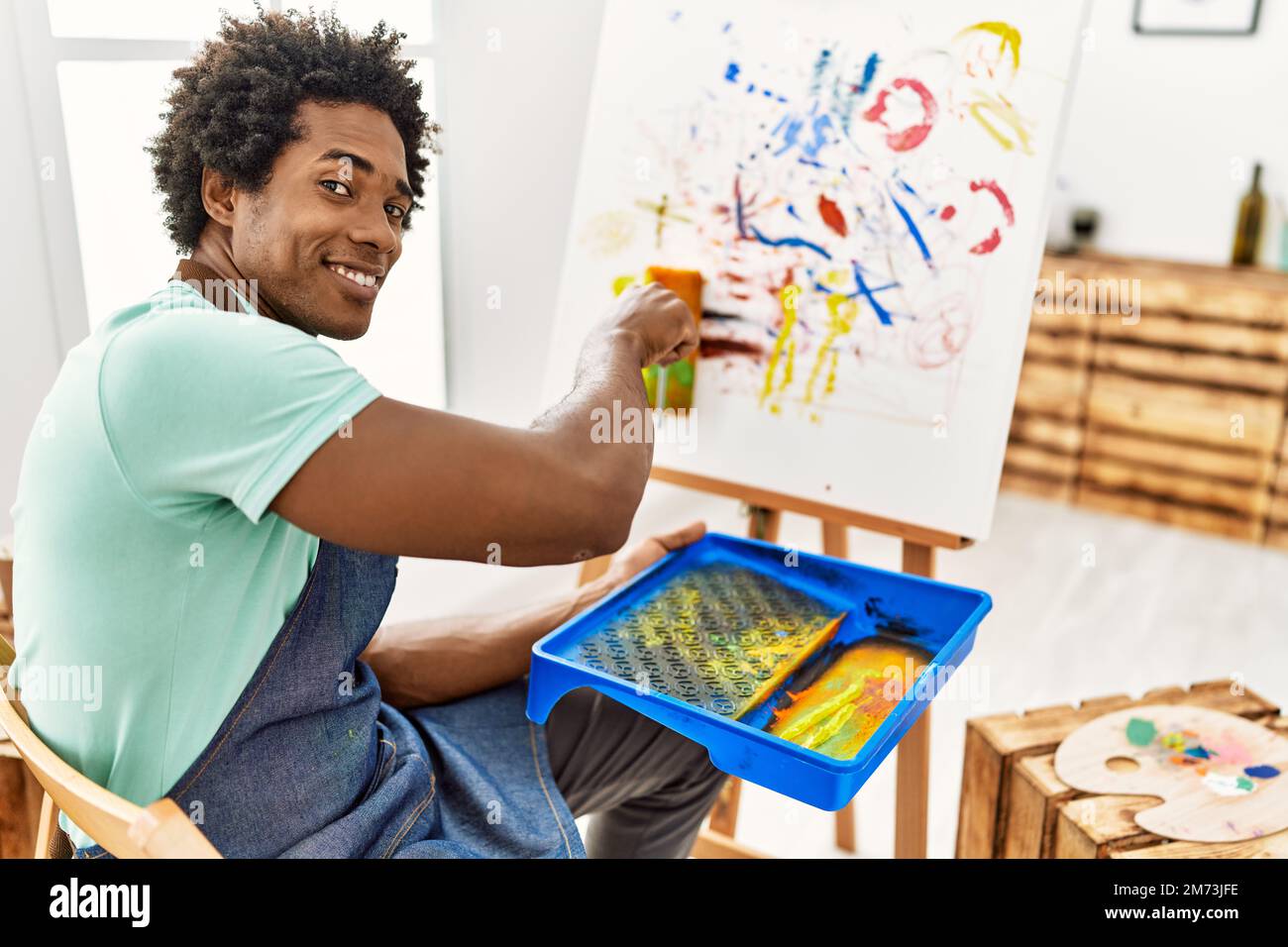 Young african american artist man drawing using paint roller at art ...