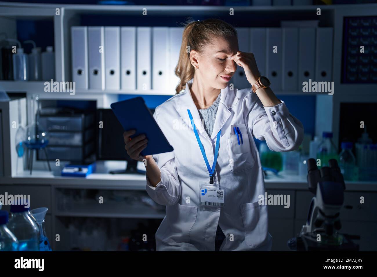 Beautiful blonde woman working at scientist laboratory late at night ...