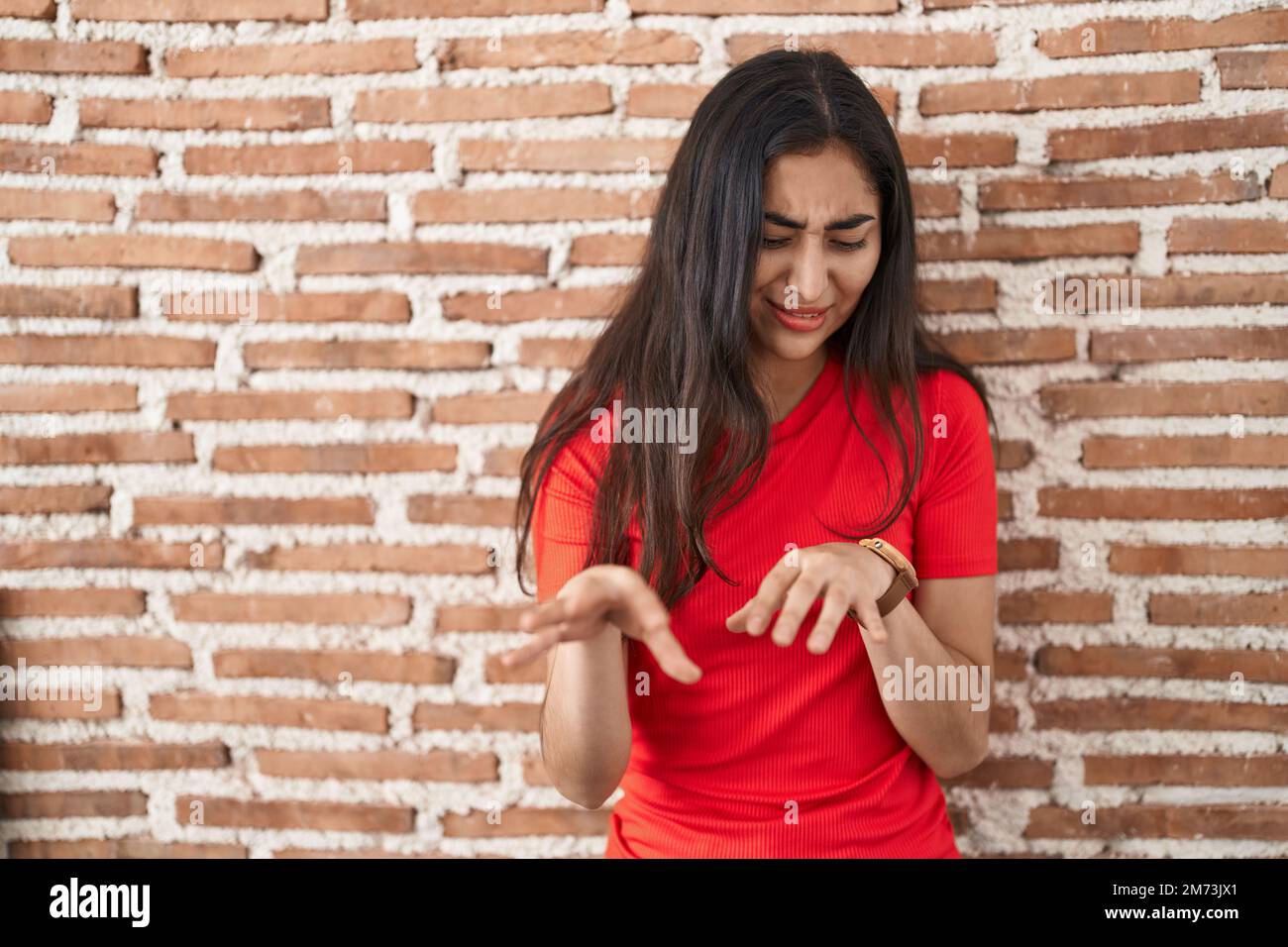 Young teenager girl standing over bricks wall disgusted expression ...
