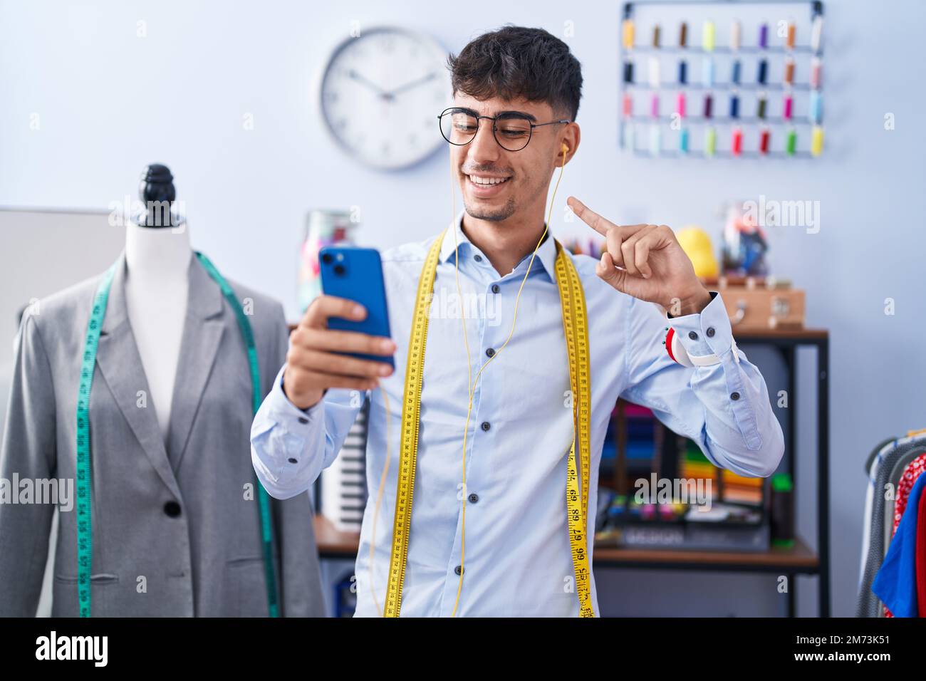 Young hispanic man dressmaker designer using smartphone smiling happy ...