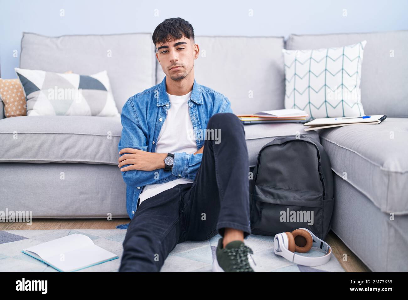 Young hispanic man sitting on the floor studying for university looking ...