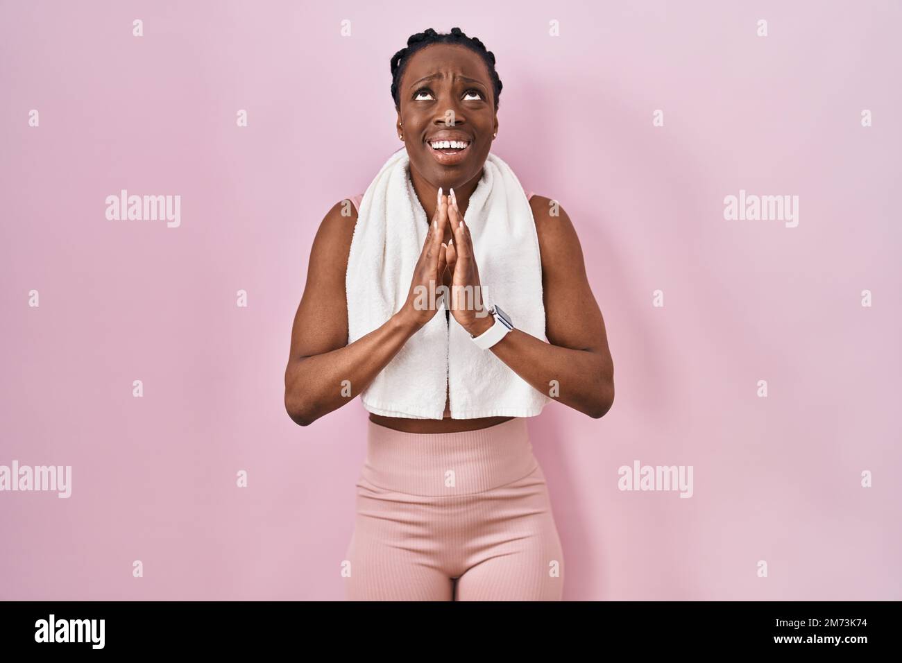 Beautiful black woman wearing sportswear and towel over pink background ...