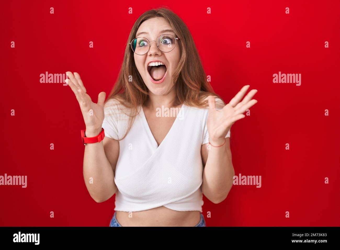 Young caucasian woman standing over red background celebrating mad and ...