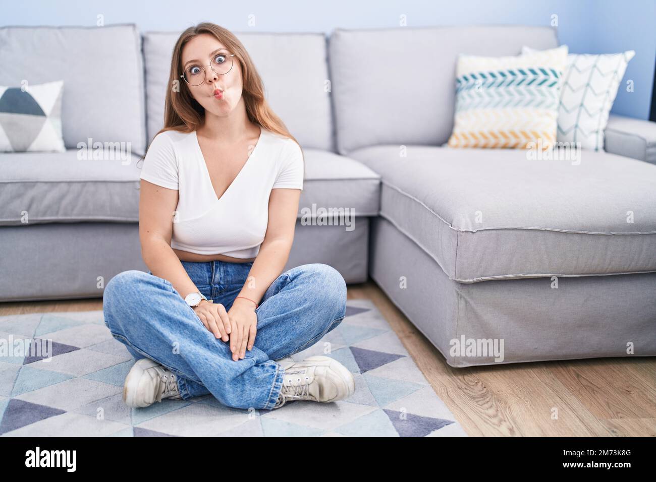 Young caucasian woman sitting on the floor at the living room making ...